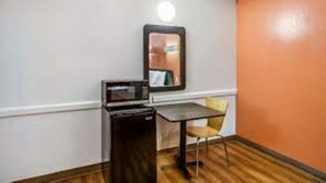 Um quarto pequeno com uma escrivaninha, cadeira e um espelho na parede.