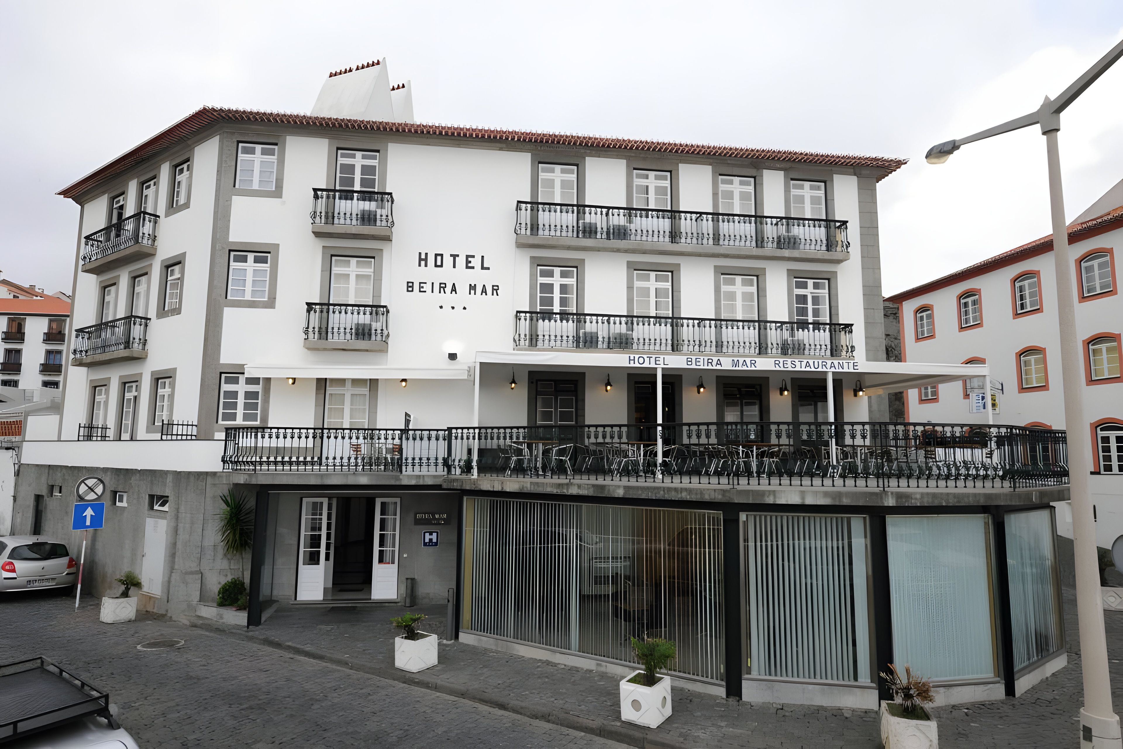 Um hotel com vários andares, varandas, restaurante no térreo e uma placa indicando entrada acessível para pessoas com deficiência.