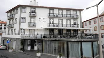 Um hotel com vários andares, varandas, restaurante no térreo e uma placa indicando entrada acessível para pessoas com deficiência.