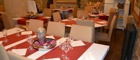 Restaurante com várias mesas, cada uma disposta com copos de vinho e um arranjo central.