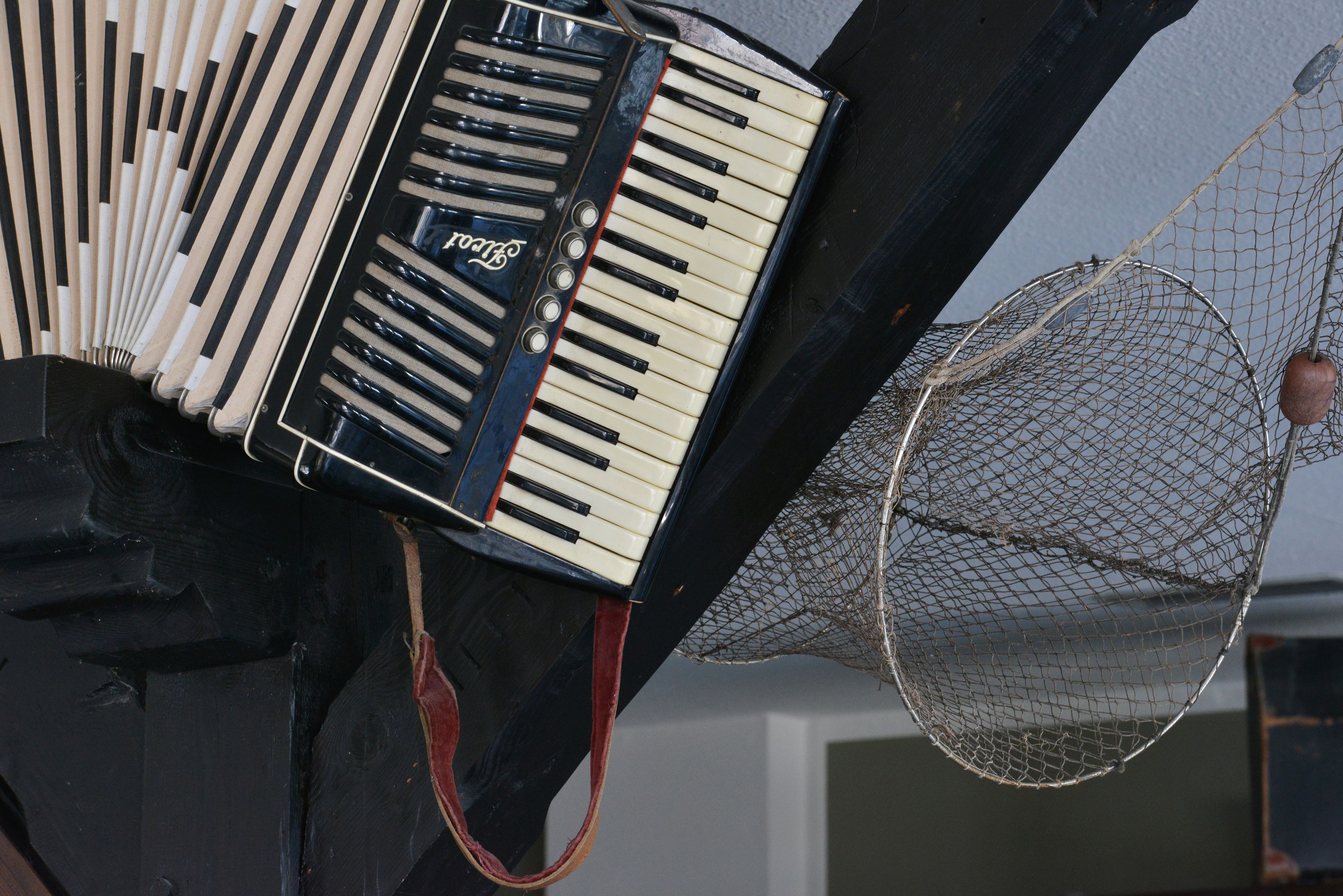 Um instrumento musical, possivelmente um acordeão, preso a uma estrutura com uma rede.