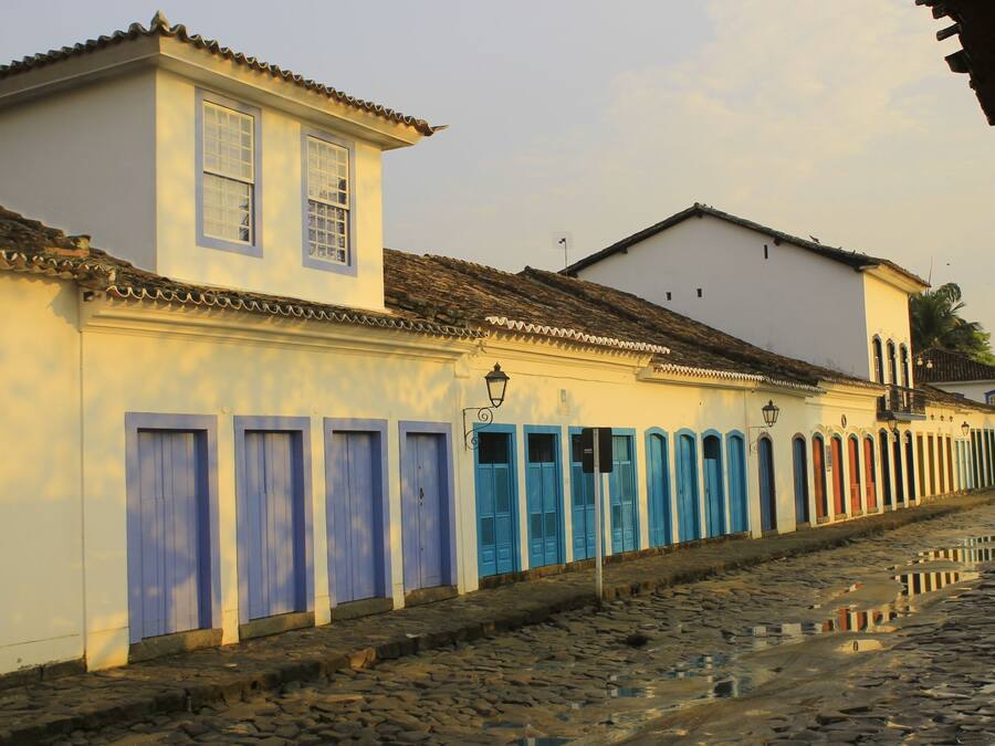 Rua com fileira de portas coloridas e caminho de pedras.