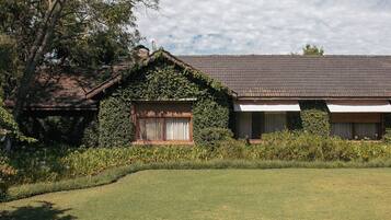 Uma casa com telhado inclinado, cercada por um gramado bem cuidado e uma grande árvore.