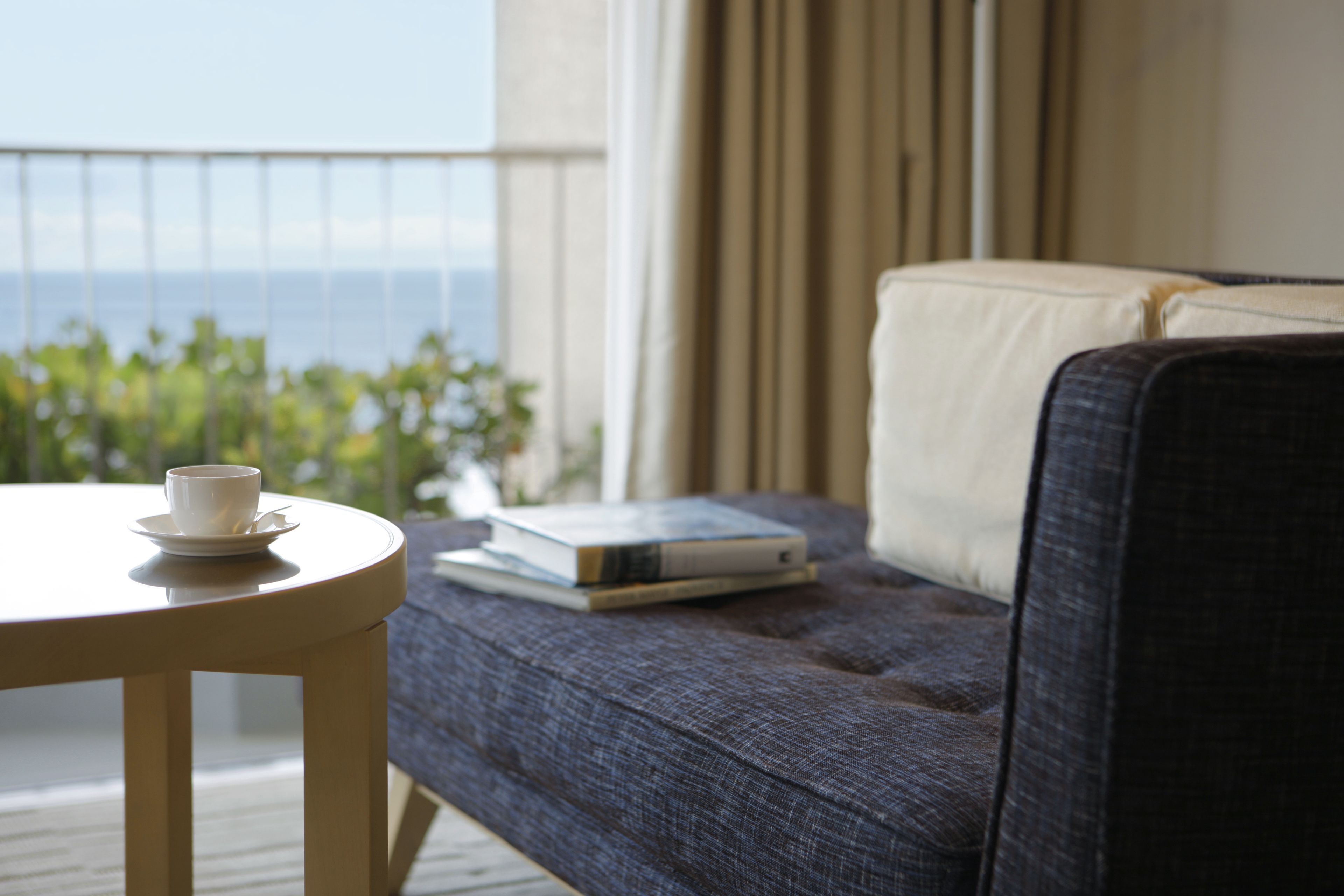 Um quarto aconchegante com uma mesa redonda, um sofá e vista para o oceano.