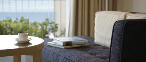 Um quarto aconchegante com uma mesa redonda, um sofá e vista para o oceano.