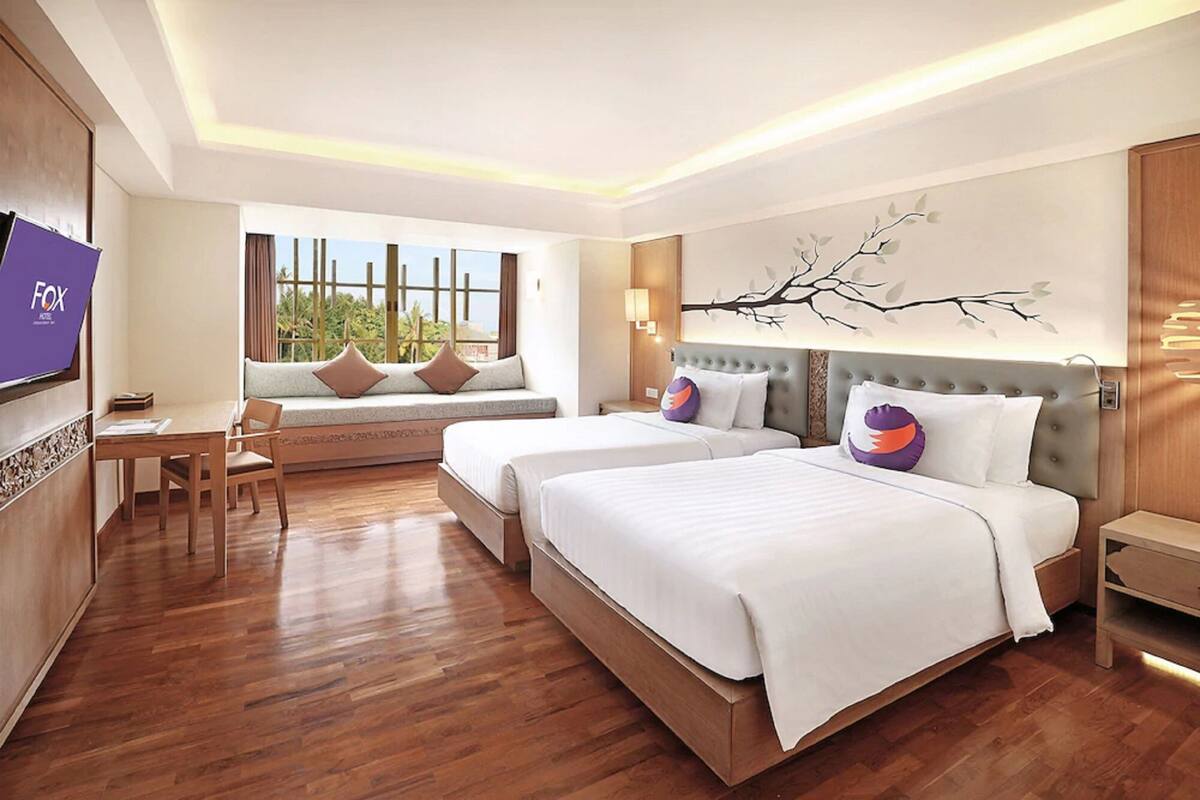 Quarto de hotel com duas camas, uma escrivaninha e uma televisão.