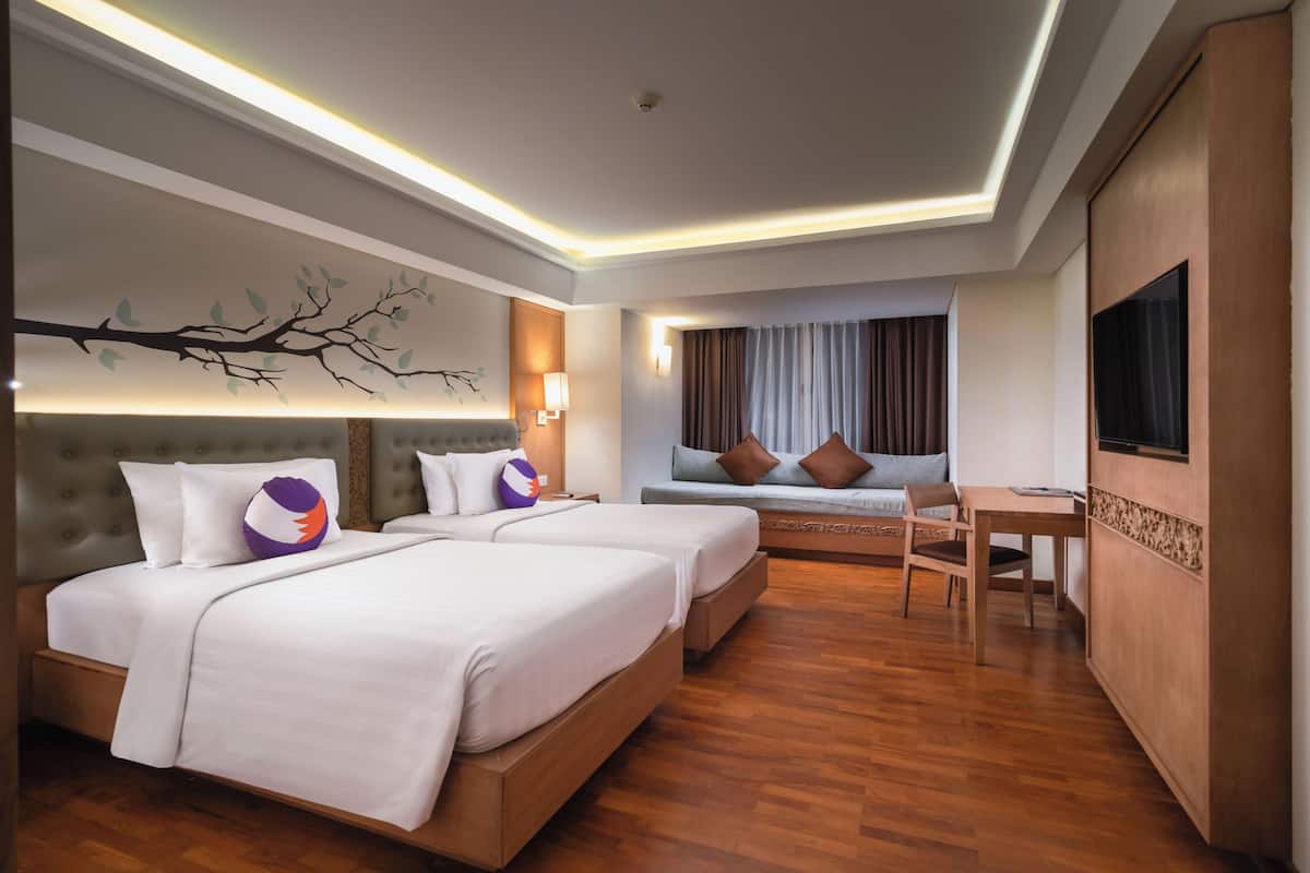 Quarto de hotel com duas camas, um sofá, uma televisão e um espaço de refeições.