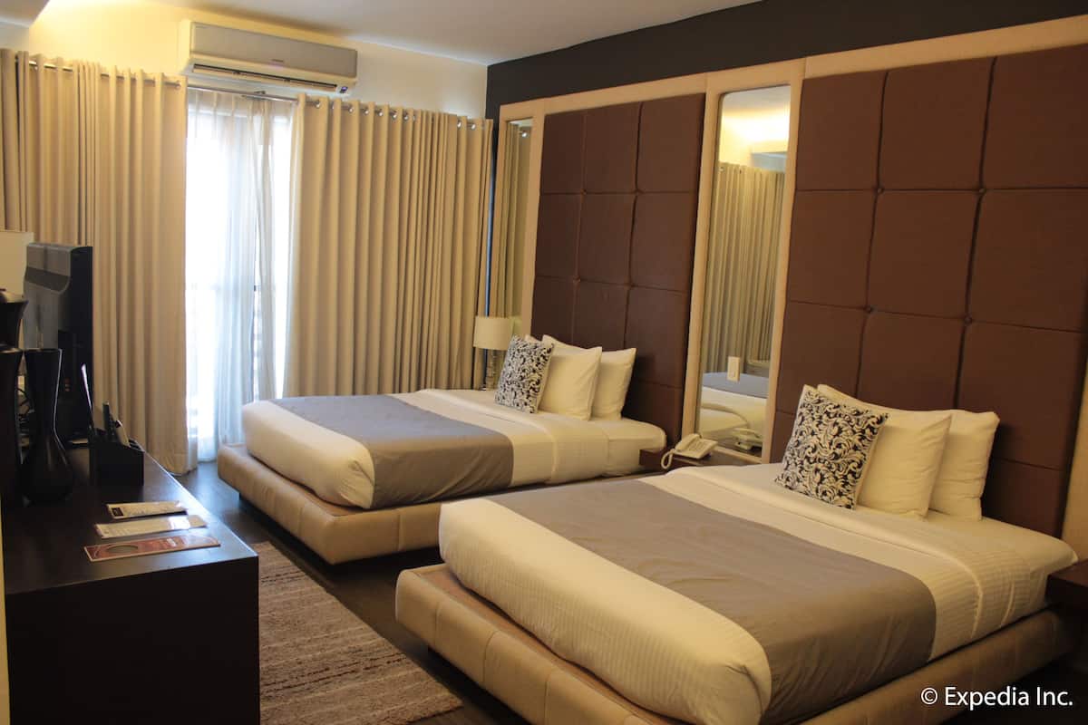 Quarto de hotel com duas camas, uma mesa com telefone e uma televisão.