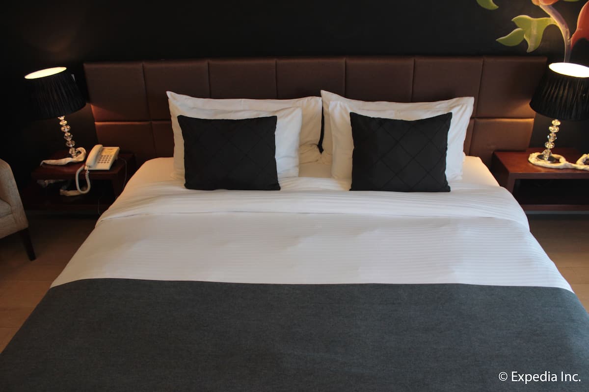 Quarto de hotel com uma cama grande, duas luminárias de cabeceira, um telefone e uma mesinha de cabeceira.