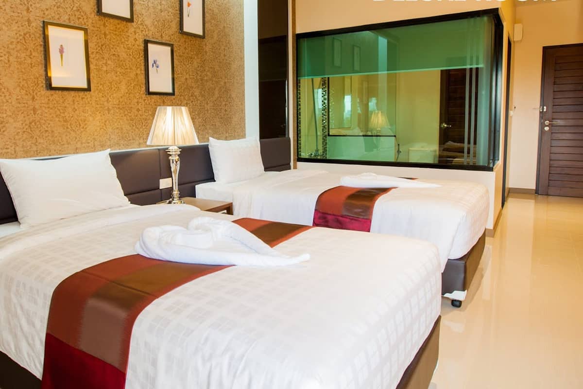 Quarto de hotel com duas camas, uma janela grande e uma parede com quadros emoldurados.