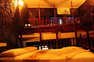 Quarto com beliche, parede de pedra e um quadro de um pássaro na parede.