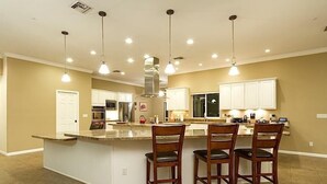 Uma cozinha espaçosa com ilha central, iluminação pendente e uma janela grande.