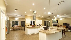 Uma cozinha ampla com ilha central, armários brancos e diversas luminárias pendentes.