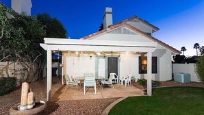 Uma casa moderna com varanda coberta, móveis de exterior e lareira de pedra.