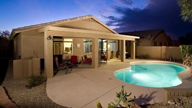 Uma casa com varanda coberta, piscina e mobiliário de exterior.