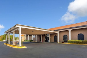Hotel com entrada coberta, fachada de tijolos e céu azul.