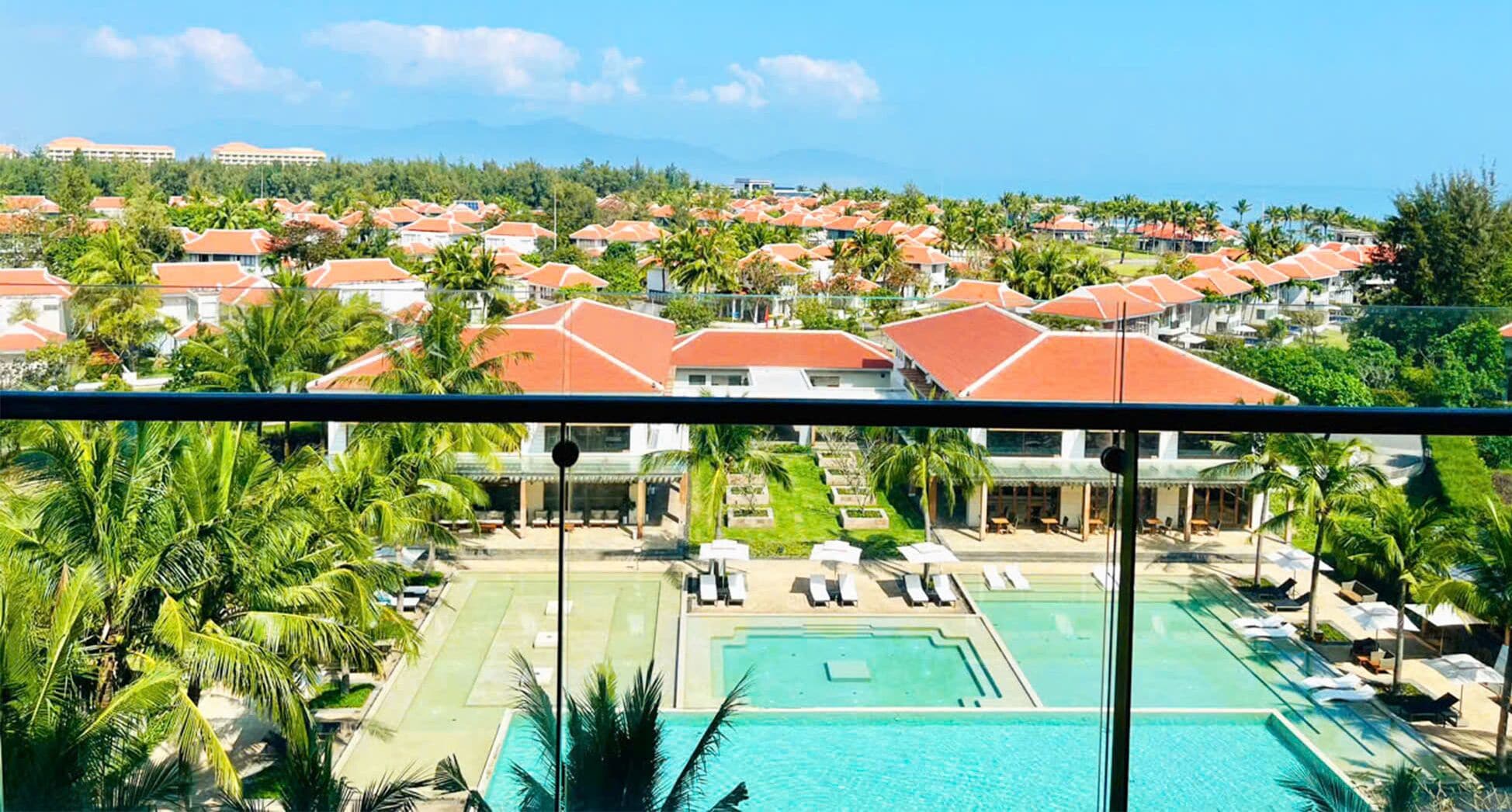 Um resort com vários edifícios, piscina e palmeiras.