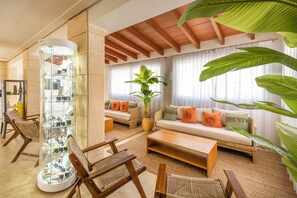 Uma sala de estar moderna com uma vitrine de vidro, um conjunto de sofás e uma planta grande.