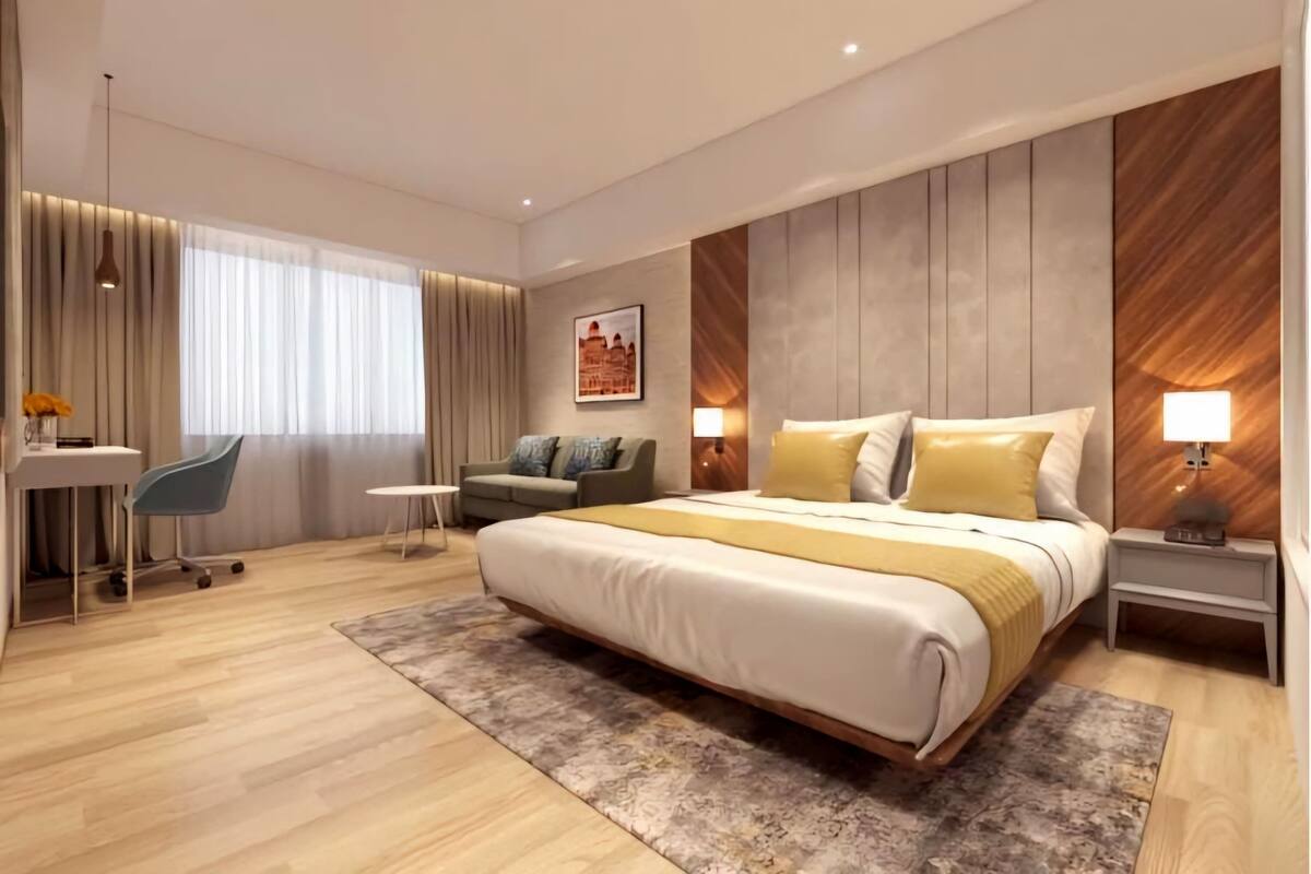 Quarto de hotel moderno com uma cama grande, uma escrivaninha, um sofá e uma pequena mesa.
