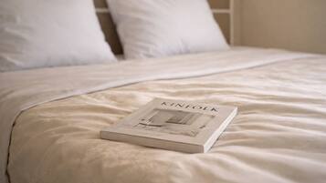 Cama bem arrumada com um livro intitulado 'KINFOLK'.