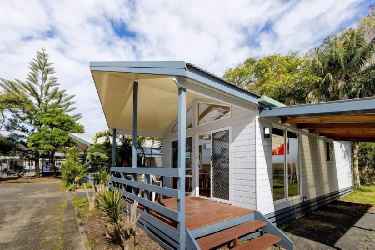 Uma casa pequena, térrea, com varanda coberta e deck de madeira.