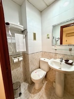 Casa de banho com sanita, lavatório e suporte para toalhas.