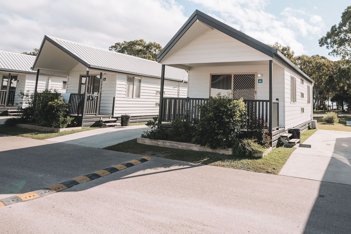Uma fileira de casas móveis com um acesso pavimentado e uma área gramada na frente.