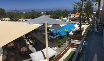 Área da piscina com vista para o mar, mobiliário de exterior e alpendre coberto.