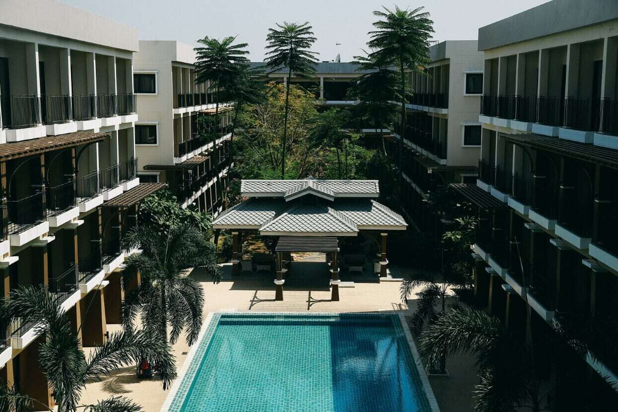 Um hotel com piscina central, várias varandas e área externa coberta.