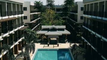 Um hotel com piscina central, várias varandas e área externa coberta.
