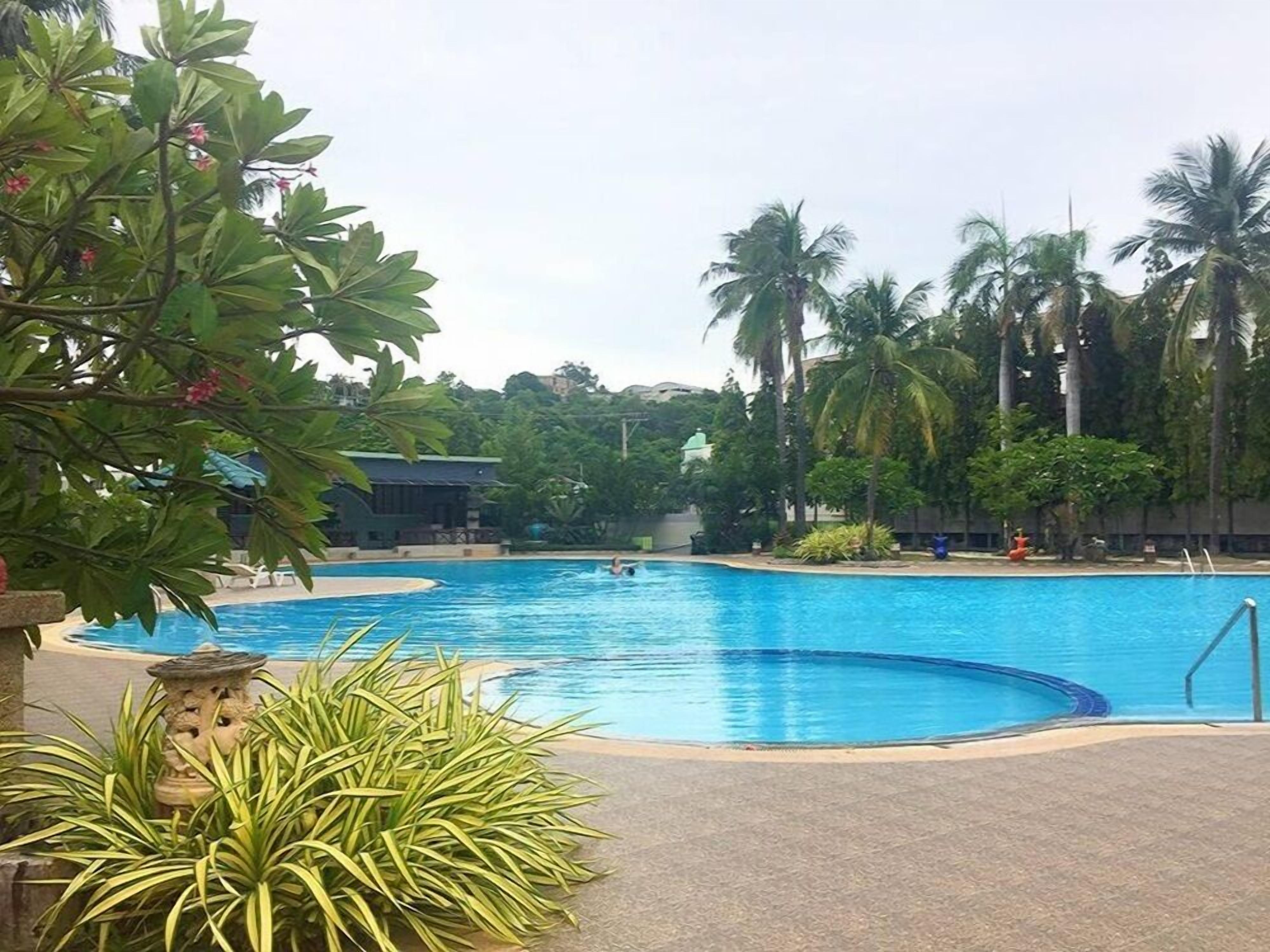 Uma grande piscina ao ar livre rodeada por palmeiras e plantas tropicais.