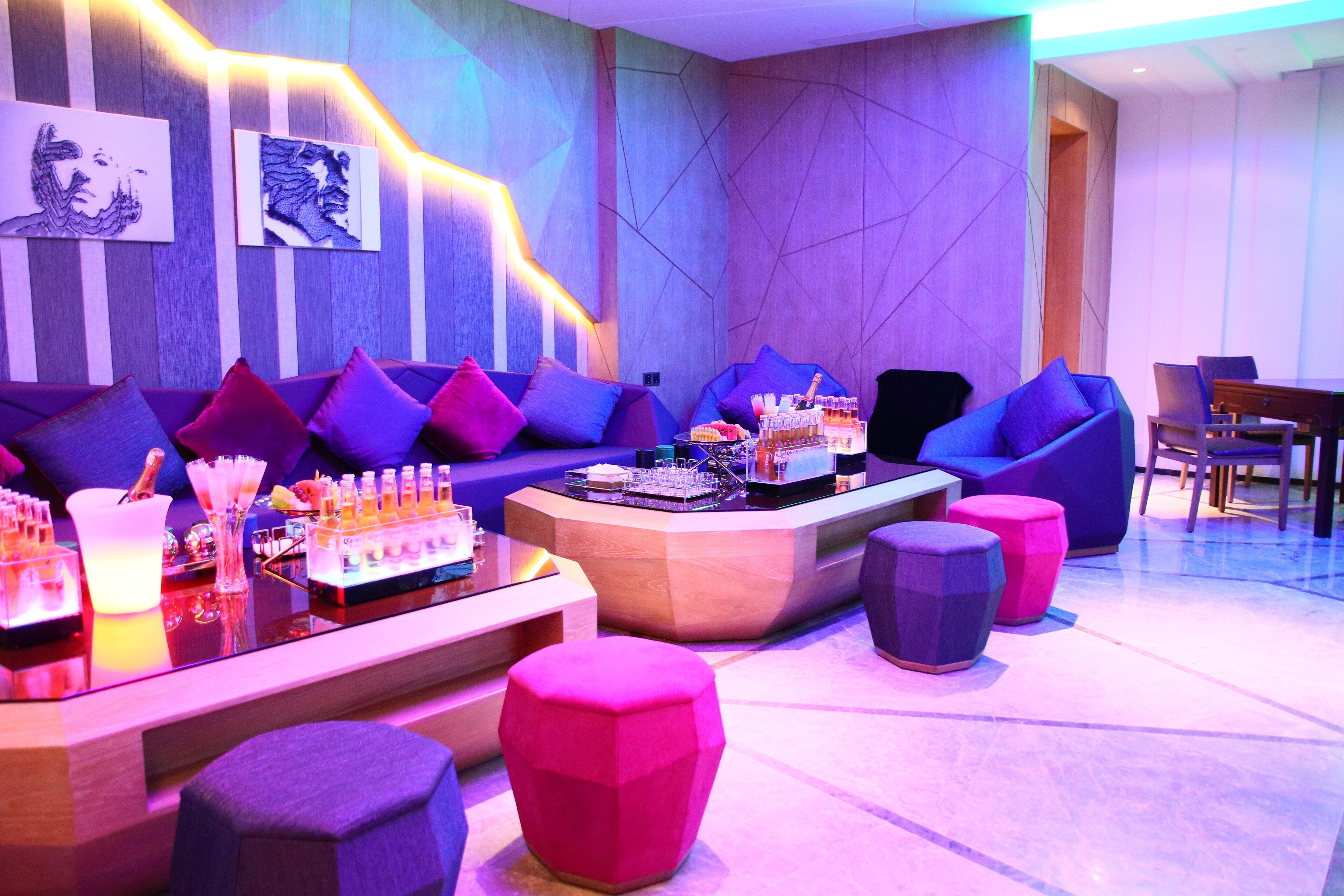 Uma área de lounge moderna com bar, assentos e obras de arte nas paredes.