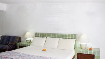 Quarto de hotel com uma cama, duas mesas de cabeceira, uma cadeira e um painel de azulejos verdes.