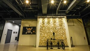 Um hall com parede de pedra, um aviso de caveira e ossos cruzados e um suporte para bicicletas.