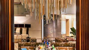 Uma área de bar moderna com disposição circular de assentos, variedade de garrafas e balcão.