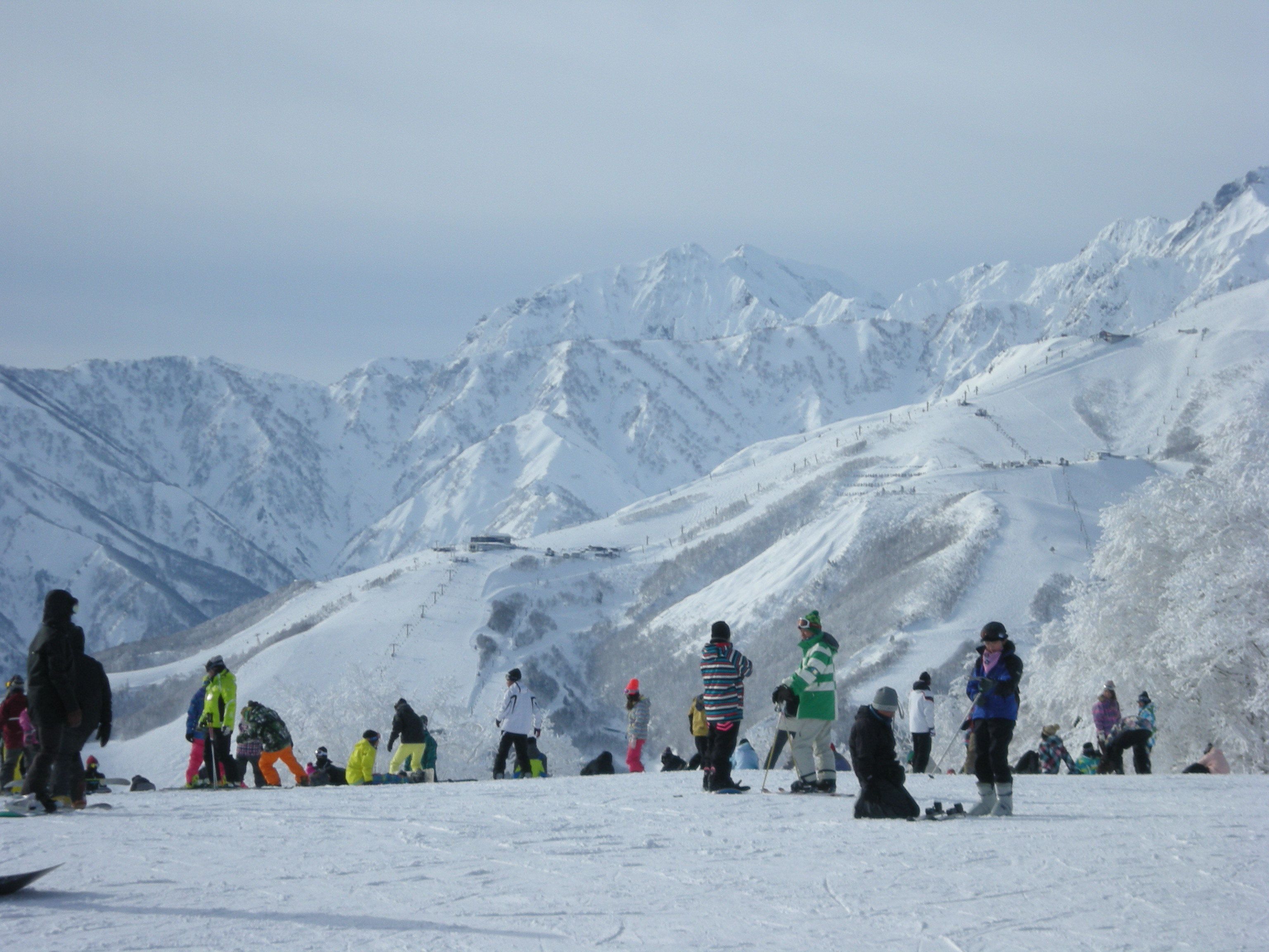 Cena nevada de montanha com esquiadores e snowboarders.