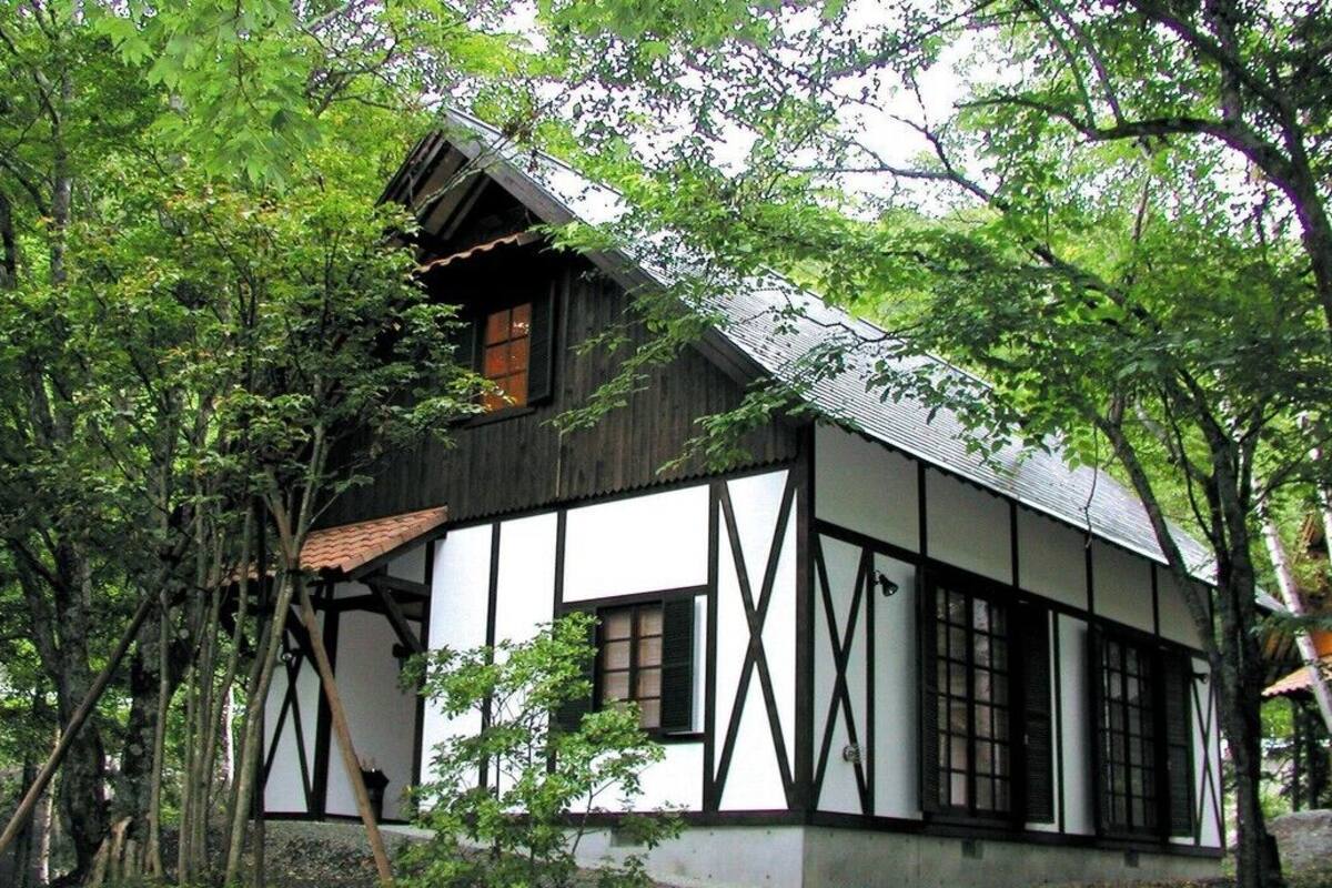 Um edifício tradicional em estilo de enxaimel com telhado inclinado, rodeado por vegetação verde exuberante.