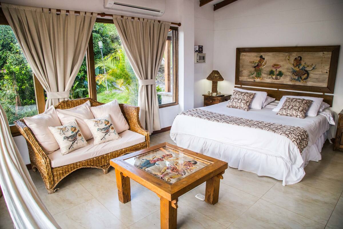 Quarto com uma cama, um sofá, uma mesa de centro e um quadro na parede.