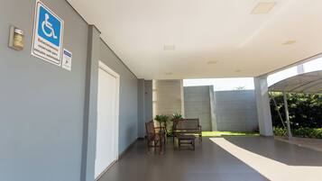 Uma área externa coberta com sinalização de acessibilidade para cadeiras de rodas, um banco e uma mesa.