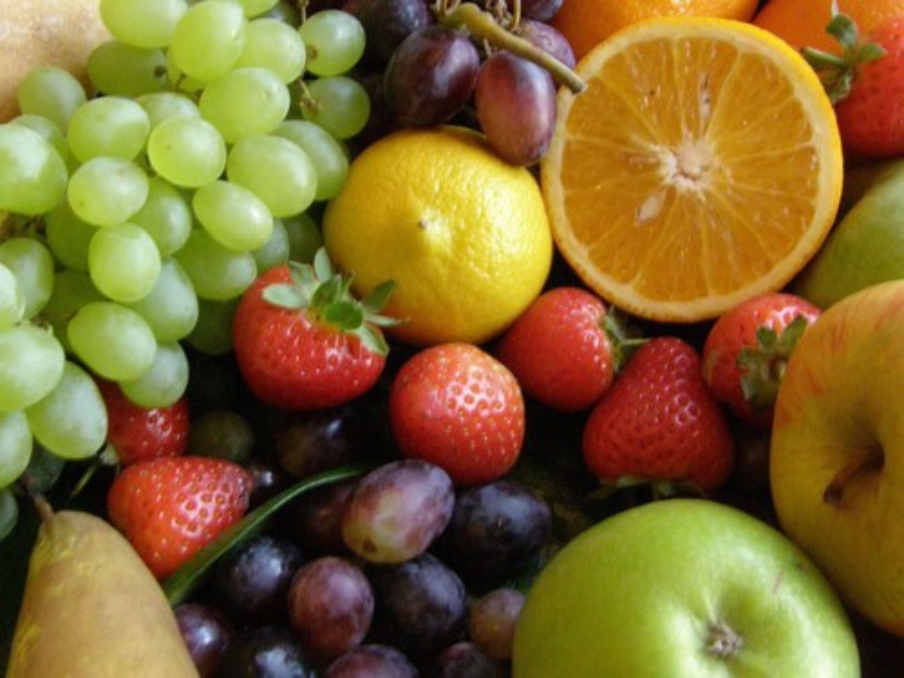 Diversas frutas, como uvas, morangos, ameixas, laranjas e maçãs.