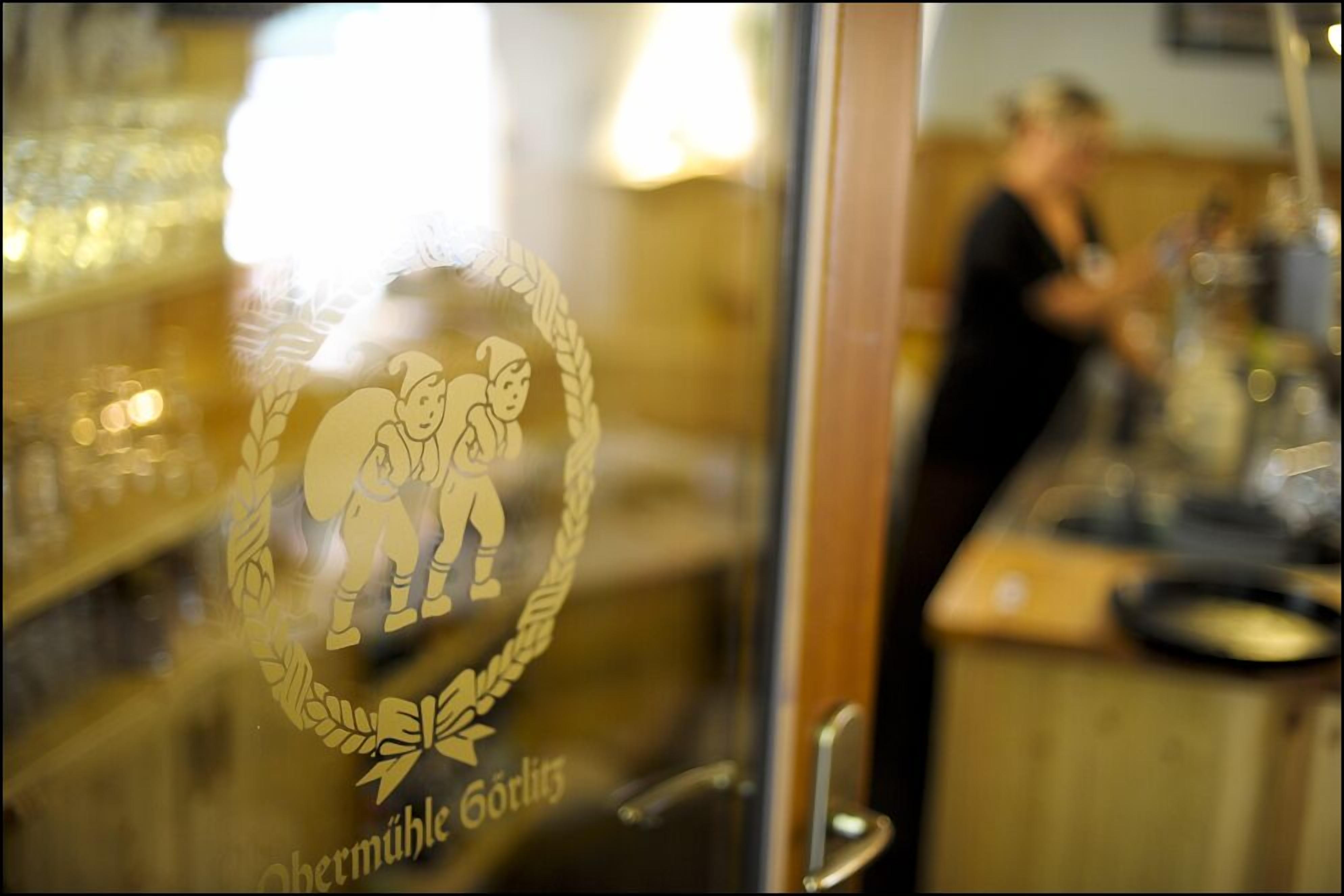 Um restaurante com um logotipo mostrando uma criança e um adulto, e o texto 'Obermühler Gärlits'.