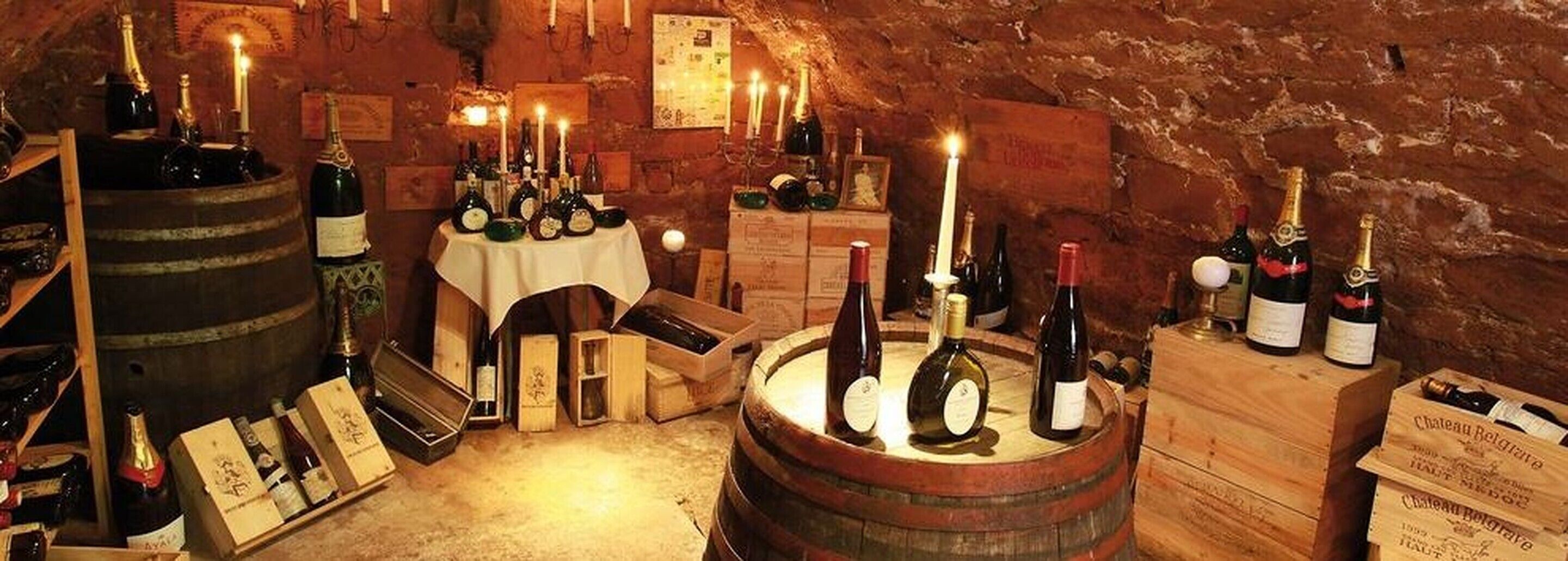 Uma adega com barris de madeira, garrafas e velas.