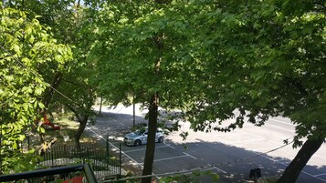 Um estacionamento com um carro, árvores e uma cerca.