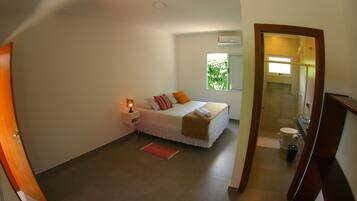 Quarto com cama, mesa de cabeceira e janela.