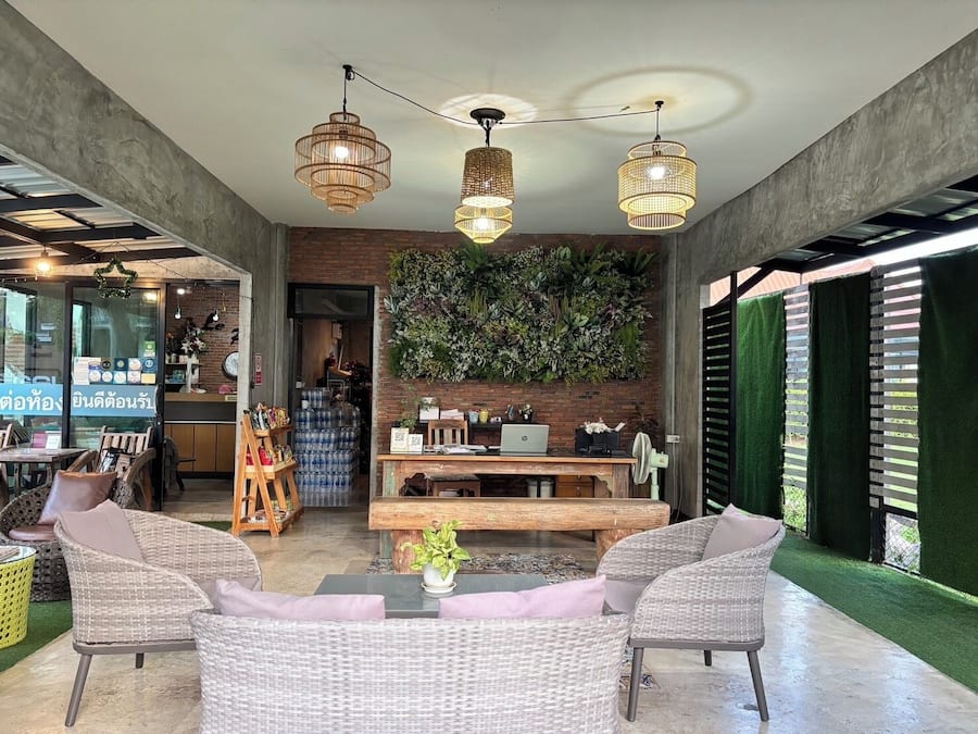 Um interior moderno com móveis de vime, uma mesa de madeira e uma parede verde com plantas.