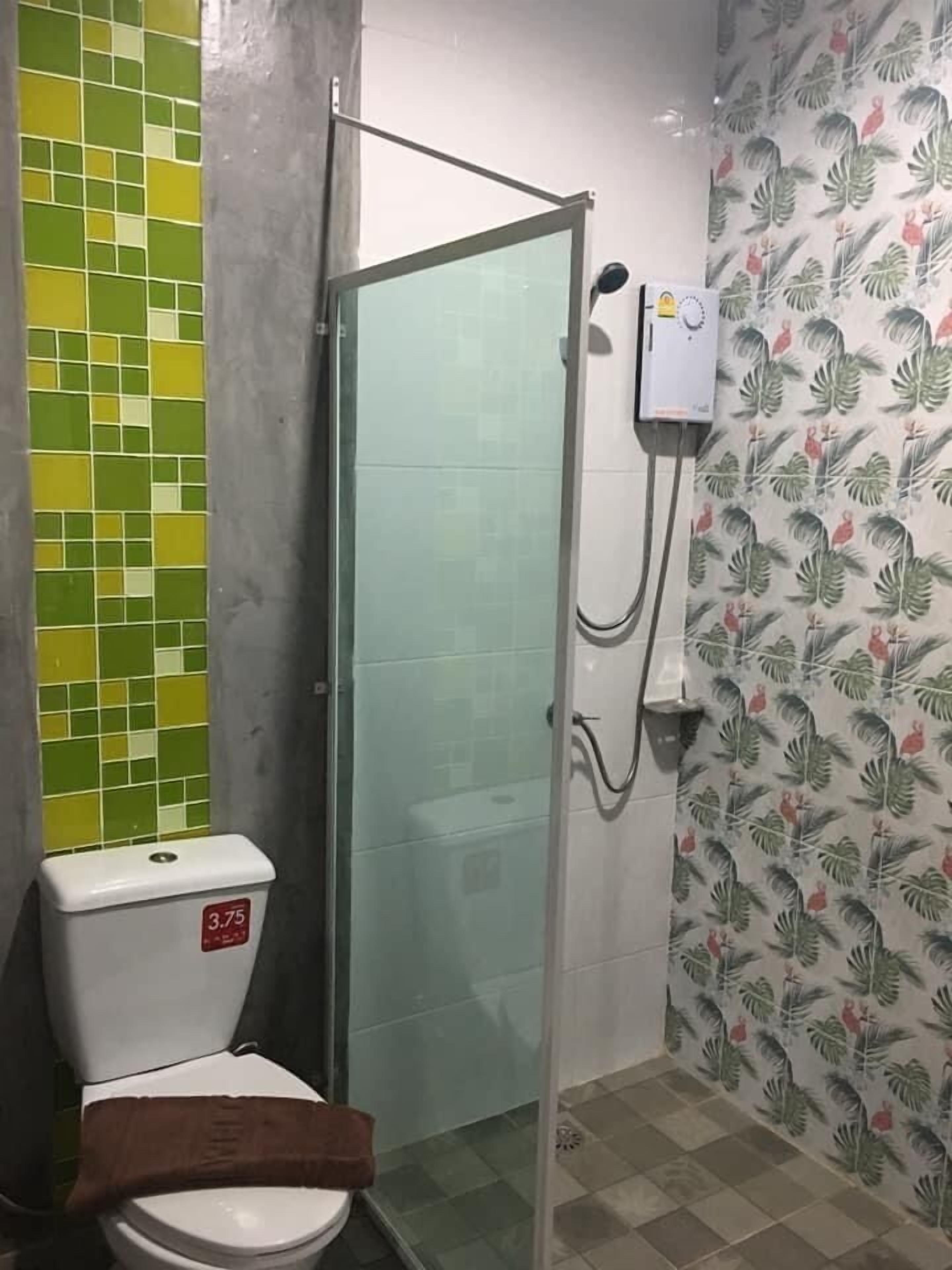 Casa de banho com sanita, cabine de duche e parede revestida a azulejos.
