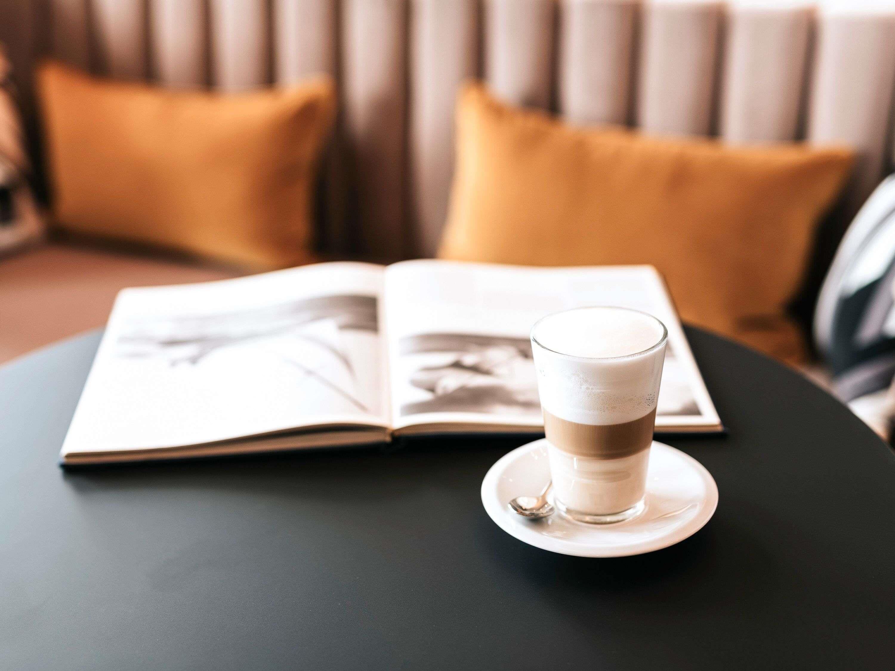 Um livro aberto sobre uma mesa, com uma xícara de café.