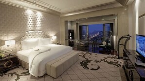 Um quarto espaçoso com uma cama grande, televisão e varanda com vista para a cidade.