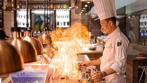 Um chef preparando comida com uma chama grande em uma cozinha moderna.