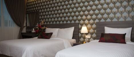 Quarto de hotel com duas camas, um painel decorativo e uma mesa de cabeceira com luminária.